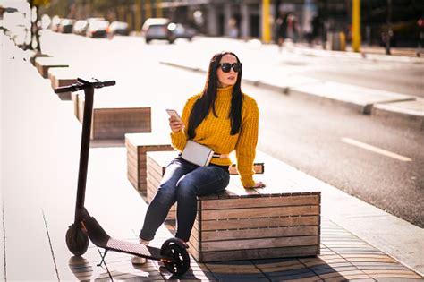 도시 거리에서 스쿠터와 자전거 차선의 벤치에 앉아있는 동안 휴대 전화를 사용 하는 현대 여자 거리에 대한 스톡 사진 및 기타