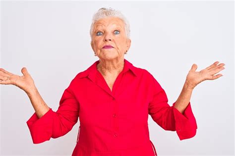 빨간 캐주얼 셔츠를 입은 선임 회색 머리 의 여자는 고립 된 흰색 배경 에 서 단서와 팔과 손을 제기 와 혼란 표정 의심 개념 감정에 대한 스톡 사진 및 기타 이미지