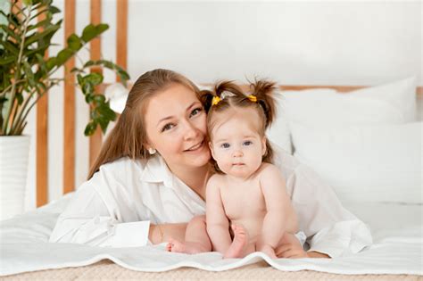 어린 딸을 가진 어머니 딸을 부드럽게 껴안고 키스하는 어머니 모성애와 보살핌 집의 침실에서 침대에 아기를 가진 행복한 가정 25 29세에 대한 스톡 사진 및 기타 이미지