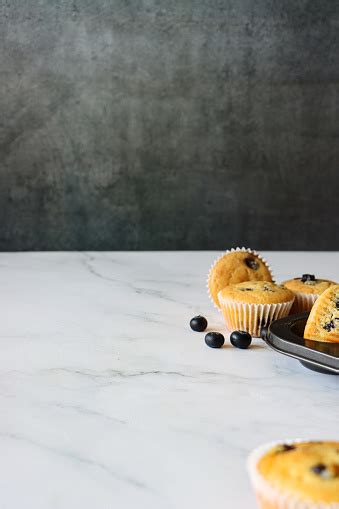 대리석 효과 표면에 신선한 블루 베리로 둘러싸인 종이 케이크 케이스에 홈 메이드 블루 베리 머핀이있는 머핀 베이킹 트레이의