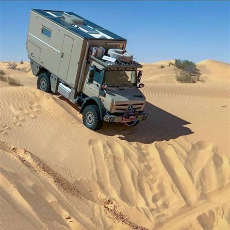 An Off Road Vehicle Driving Through The Desert With Its Trailer
