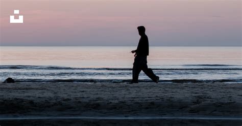 사람은 일몰 동안 해변을 걷습니다 사진 Unsplash의 무료 바닷가 이미지