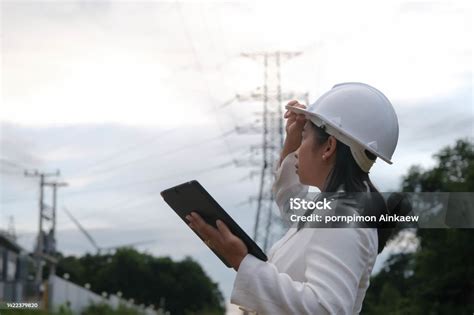 고전압 극 근처의 노트북에서 일하는 아시아 여성 전기 엔지니어 전력망 검사 풍력 터빈 엔지니어 전력 생산 재생 가능 에너지 개념