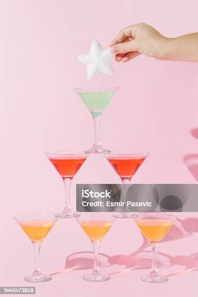 분홍색 배경에 별과 여자의 손이 있는 크리스마스 트리 모양으로 배열된 화려한 칵테일 잔 새해 파티 또는 축하 최소한의 개념 초현실주의에 대한 스톡 사진 및 기타 이미지