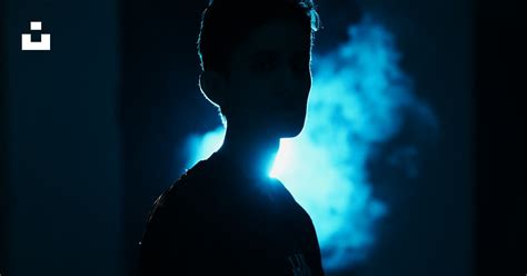 입에서 연기가 나오는 어두운 방에 서 있는 남자 사진 Unsplash의 무료 이미지