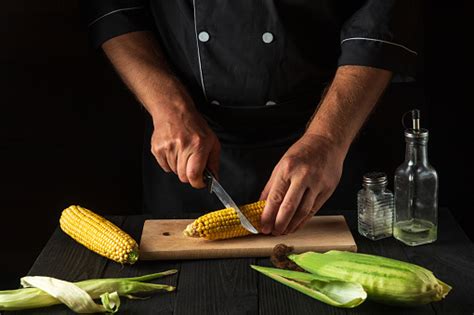 요리사는 칼로 신선한 옥수수를 자릅니다 삶은 옥수수는 아침이나 점심을위한 훌륭한 식단입니다 레스토랑 주방 테이블의 작업 환경 개체 그룹에 대한 스톡 사진 및 기타 이미지