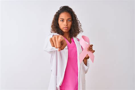 카메라와 당신에 게 손가락으로 가리키는 고립 된 흰색 배경 위에 암 리본을 들고 젊은 브라질 의사 여자 손 기호 앞에서 긍정적이 고 자신감 제스처 가리키기에 대한 스톡 사진