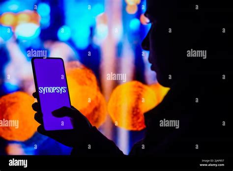 In This Photo Illustration A Silhouetted Woman Holds A Smartphone With The Synopsys Inc Logo