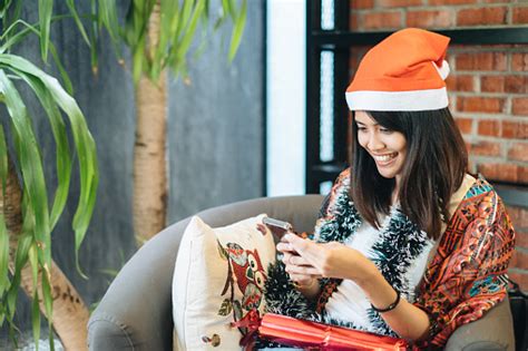 크리스마스 모자를 쓰고는 말레이시아 여자 들고 스마트폰 20 29세에 대한 스톡 사진 및 기타 이미지 20 29세 25