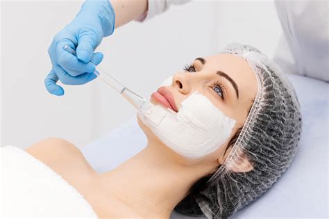 미용사가 화장품 브러시로 젊고 아름다운 여성의 얼굴에 점토 마스크를 바릅니다 20 24세에 대한 스톡 사진 및 기타 이미지 20 24세 가꿔주기 건강관리와 의술