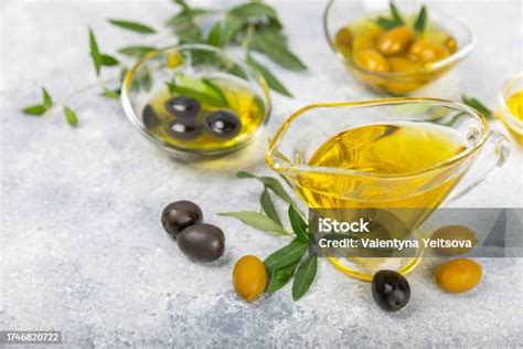 유리 그릇에 담긴 올리브 오일 그레이비 보트 질감이 있는 식탁에 담긴 병 올리브의 가지와 열매가 달린 기름 병 텍스트를 위한 위치입니다 복사 공간 식용유와 샐러드 드레싱
