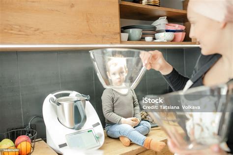 만화 놀라운 귀여운 금발 소년은 나무 부엌 서랍에 앉아 여자 손에 투명 그릇을 통해 카메라를 보고 있습니다 18 23 개월에 대한 스톡 사진 및 기타 이미지 Istock