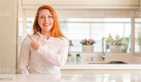 손과 카메라 보고 얼굴에 행복 하 고 자연 식 가진 측까지 손가락으로 가리키는 얼굴의 미소와 밝은 부엌에서 빨강 머리 여자 가리키기에 대한 스톡 사진 및 기타 이미지