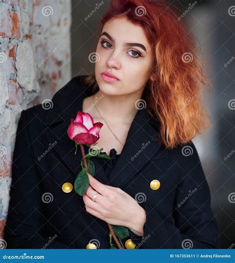 Een Mooi Rood Harig Jong Meisje In Een Zwarte Jas Met Een Roze Roze Roze Roos In Haar Hand Stelt