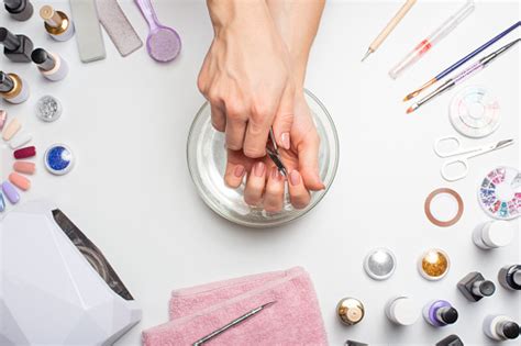 네일 케어 손톱을 만드는 아름 다운 여자 손에 흰색 바탕에 분홍색 부드러운 매니큐어 페인트 여자의 손에 근처 전문 매니큐어 도구 세트 뷰티 케어입니다 높은 해상도 가꿔주기에