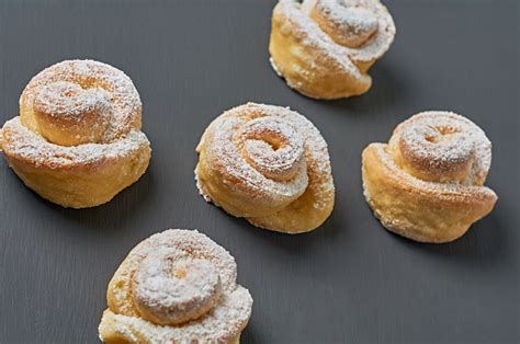 가루 설탕의 장미 스팽글 형태로 흩어져 만든 구운 빵은 어두운 콘크리트 책상에 놓여있다 제과 작업장 클로즈업 가루 설탕에 대한