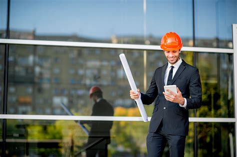 태블릿을 사용하여 프로젝트와 하드 모자를 가진 젊은 건설 엔지니어 남자 건물 외관에 대한 스톡 사진 및 기타 이미지 건물