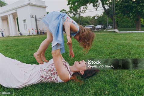 빛 드레스에 즐거운 여자 녹색 잔디 나머지에 거짓말을 작은 귀여운 아이 아가 발생 재생 하 고 재미 어머니 딸 아이입니다 어머니의 날 사랑 가족 부모 어린 시절 컨셉 2명에