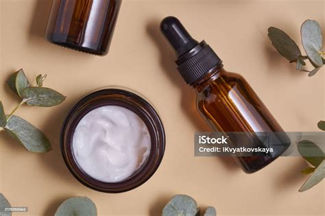 노화 방지 콜라겐 페이셜 세럼은 어두운 유리 병과 유칼립투스가 있는 베이지색 배경에 페이스 크림입니다 천연 유기농 화장품 뷰티 컨셉 브랜딩을 위한 모형 0명에 대한 스톡