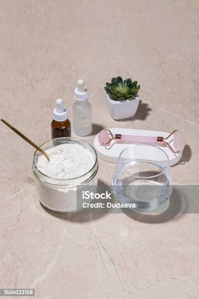 물 한 잔과 콜라겐 한 병이 대리석 베이지색 배경에 있습니다 가정 미용 절차 콜라겐과 펩타이드가 함유 된 음료와 세럼 페이셜