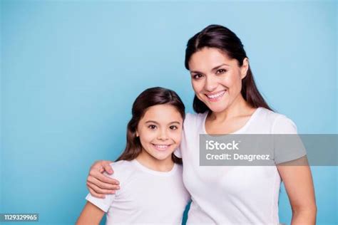 사진 놀라운 두 사람 갈색 머리 엄마 작은 작은 딸 서 포옹 사랑 스러운 자유 시간을 꽤 가까이 밝은 파란색 배경에 고립 된