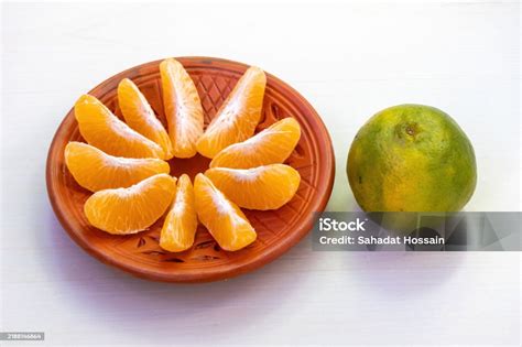 껍질을 벗긴 달콤한 오렌지 과즙이 많은 조각이 점토 접시에 있고 나무 배경에 오렌지 전체가 근처에 있습니다 감귤에 대한 스톡 사진 및 기타 이미지 Istock