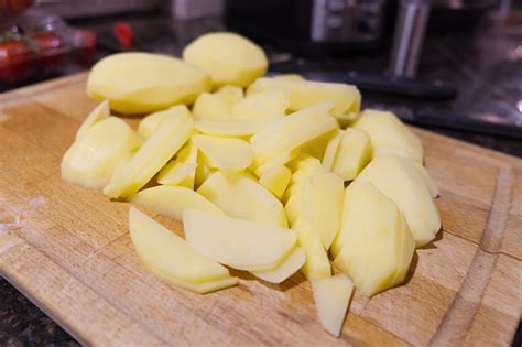 집에서 요리할 준비가 된 나무 도마에 얇게 썬 생 감자 부엌 복사 공간이 있는 클로즈업 음식 사진 집에서 요리 수제 요리 채식주의자 또는 비건 식단 0명에 대한 스톡 사진