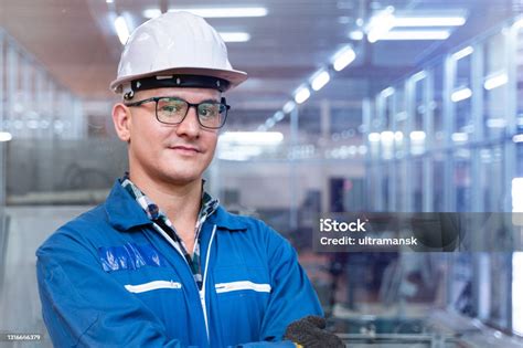 엔지니어 맨 워커의 얼굴을 클로즈업하는 것은 첨단 기술 청정 산업 공장의 유리 벽 앞에 있는 멋진 드레스와 헬멧을 위해 파란색 작업 스위트 그린 반사로 자신감을 가지고 서