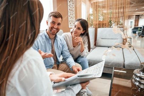 Premium Photo Woman Helping Couple With Choosing The Sofa And Bed In