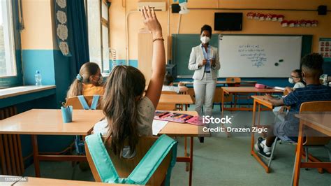 교실에서 수업 중에 교사의 질문에 대답하기 위해 팔을 들고 있는 여학생의 뒷모습 아이에 대한 스톡 사진 및 기타 이미지 아이 보호 마스크 학교 건물 Istock