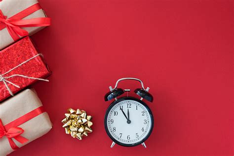 왼쪽에 리본이 있는 검은 둥근 시계와 나무 선물 상자의 평평한 평지가 빨간색 배경에 놓여 있으며 텍스트를 복사합니다 개념에 대한 스톡 사진 및 기타 이미지 Istock