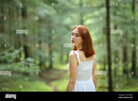 Beautiful Woman Walking Alone In A Green Forest Looking At Camera In