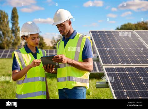 Male And Female Engineers With Digital Tablet Inspecting Solar Panels