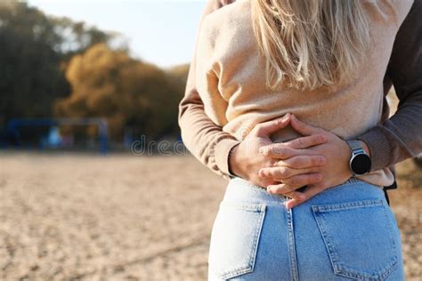 A Young Man Hugs A Girl In Jeans And A Sweater Around The Waist Fingers Crossed On Her Back