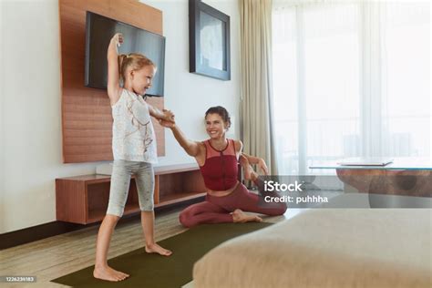 운동 집에서 스트레칭 부모와 아이 행복한 어머니와 딸은 거실에서 함께 운동합니다 요가 매트에 연습 하는 어린 소녀와 젊은 여자 2명에 대한 스톡 사진 및 기타 이미지