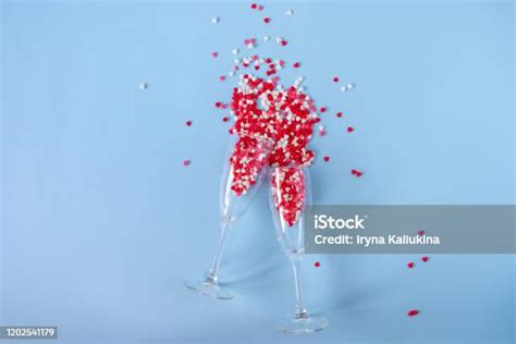빨간 하트 모양의 설탕 사탕의 스플래시와 두 개의 샴페인 안경 파란색 배경 위에 발렌타인 데이 기념일 또는 결혼 축하 개념입니다