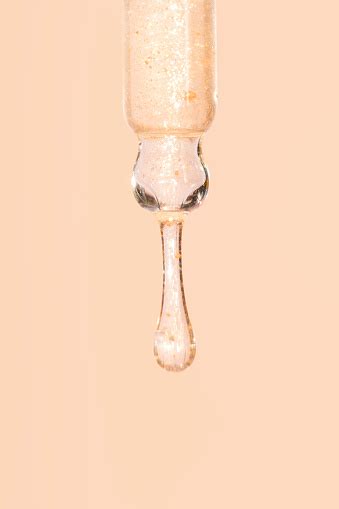 베이지색 배경에 아름다운 반짝이는 쏟아지는 페이스 세럼이 있는 피펫 스포이드의 매크로를 닫습니다 금색에 대한 스톡 사진 및 기타 이미지 Istock