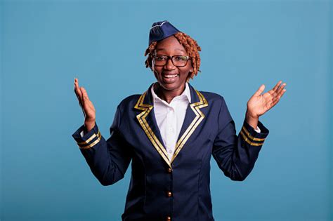 전문 여성 승무원이 비행기 객실에 도착하는 승객을 행복하게 맞이합니다 스튜어디스 유니폼을 입은 여자가 파란색 배경을 배경으로 스튜디오에서 카메라를 보고 있다 공항에 대한