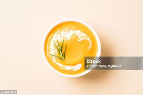 밝은 배경 위에 헤비 크림과 로즈마리로 장식된 흰색 그릇에 담긴 두꺼운 버터넛 스쿼시 비스크 호박과 당근 크림 수프 한 그릇 오버헤드 보기 선택적 초점 수프에 대한 스톡