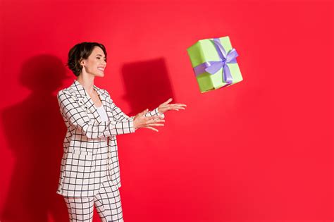 프로필 측 사진 의 젊은 쾌활한 소녀 행복 긍정적인 미소 수신 현재 공기 비행 고립 된 빨간 색 배경 갈색 머리에 대한 스톡