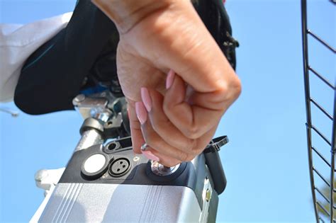 핑크 손톱과 매니큐어 여자 전기 자전거 배터리 팩의 키를 잡으십시오 화창한 여름 날에 공원에서 키 여성 스위치 전원된 전자 자전거 아래에서 총 닫습니다 건강한 생활방식에