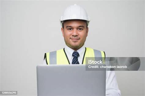 아시아 토목 엔지니어는 스튜디오에서 작업을 제어하기 위해 노트북으로 작동합니다 고립 된 흰색 배경에 서 노트북 컴퓨터를 사용하여 하드 모자를 착용 하는 노동자 개발에 대한