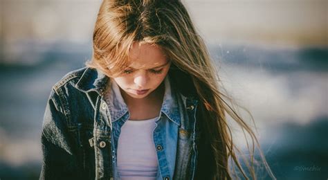 Обои на рабочий стол Девочка с длинными волосами сидит в траве с отцветшими одуванчиками в руке