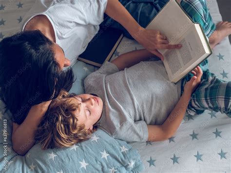 Mother And Preteen Son Lying On Bed And Reading Stock Photo Adobe Stock
