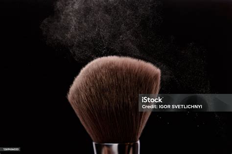 검은 색 배경에 베이지 색 분말 폭발 메이크업 브러시 창조적 인 스플래시 전문 파우더 반짝이는 페이스 파우더의 구름을 방출하는 화장품 브러쉬 공간을 복사합니다 뷰티 및