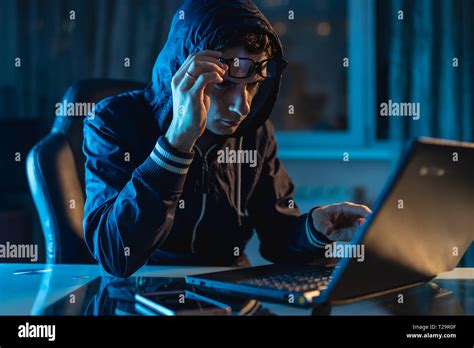 a male hacker in glasses thinking about the problem of hacking and stealing access databases