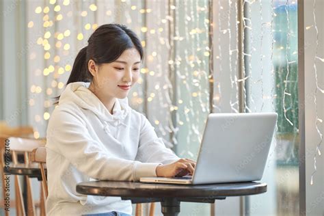 아시아 한국의 카페 테이블에 앉아서 노트북을 바라보며 강의를 듣거나 숙제 또는 일을 하는 젊은 여자 대학생 모델 Stock
