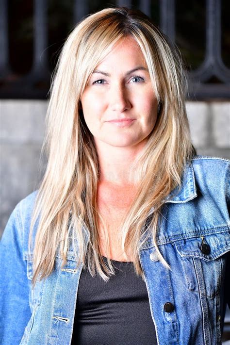 Woman Smiling In A Blue Denim Jacket With Long Blonde Hair Outside At