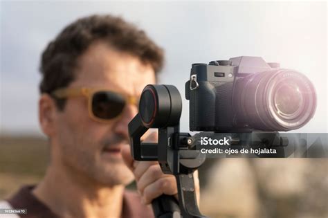 3 축 야외 Vlogger 짐벌 녹화 콘텐츠 디지털 카메라 안정제 짐벌 보관 비디오를위한 여행을 문서화하는 카메라를 손에 든 남자 짐벌을 손에 들고 비디오 그래퍼 개념