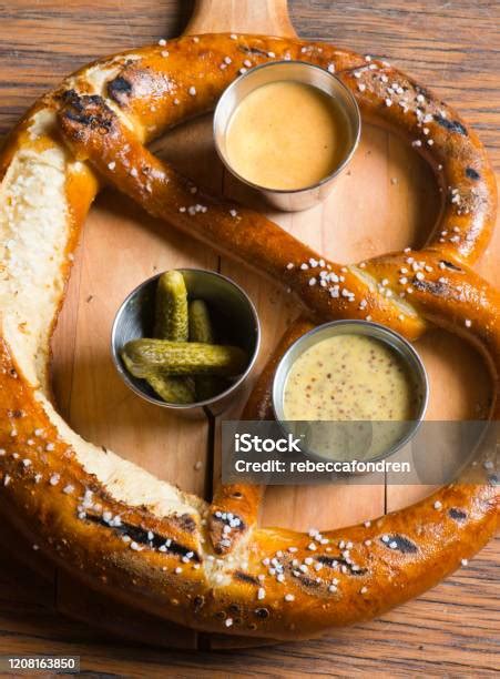 프레첼 나무 도마에 굵은 소금을 곁들인 갓 구운 부드러운 프레첼 통곡물 겨자 코니콘 피클 꿀 겨자와 함께 제공됩니다 근접 촬영 0명에 대한 스톡 사진 및 기타 이미지